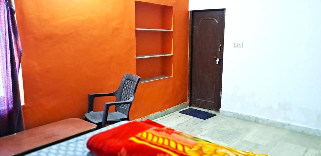Quarto com uma cadeira, porta e estante em parede laranja.