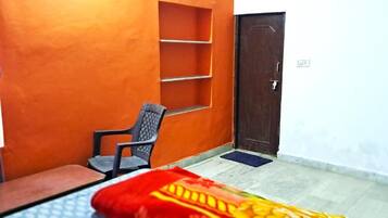 Quarto com uma cadeira, porta e estante em parede laranja.