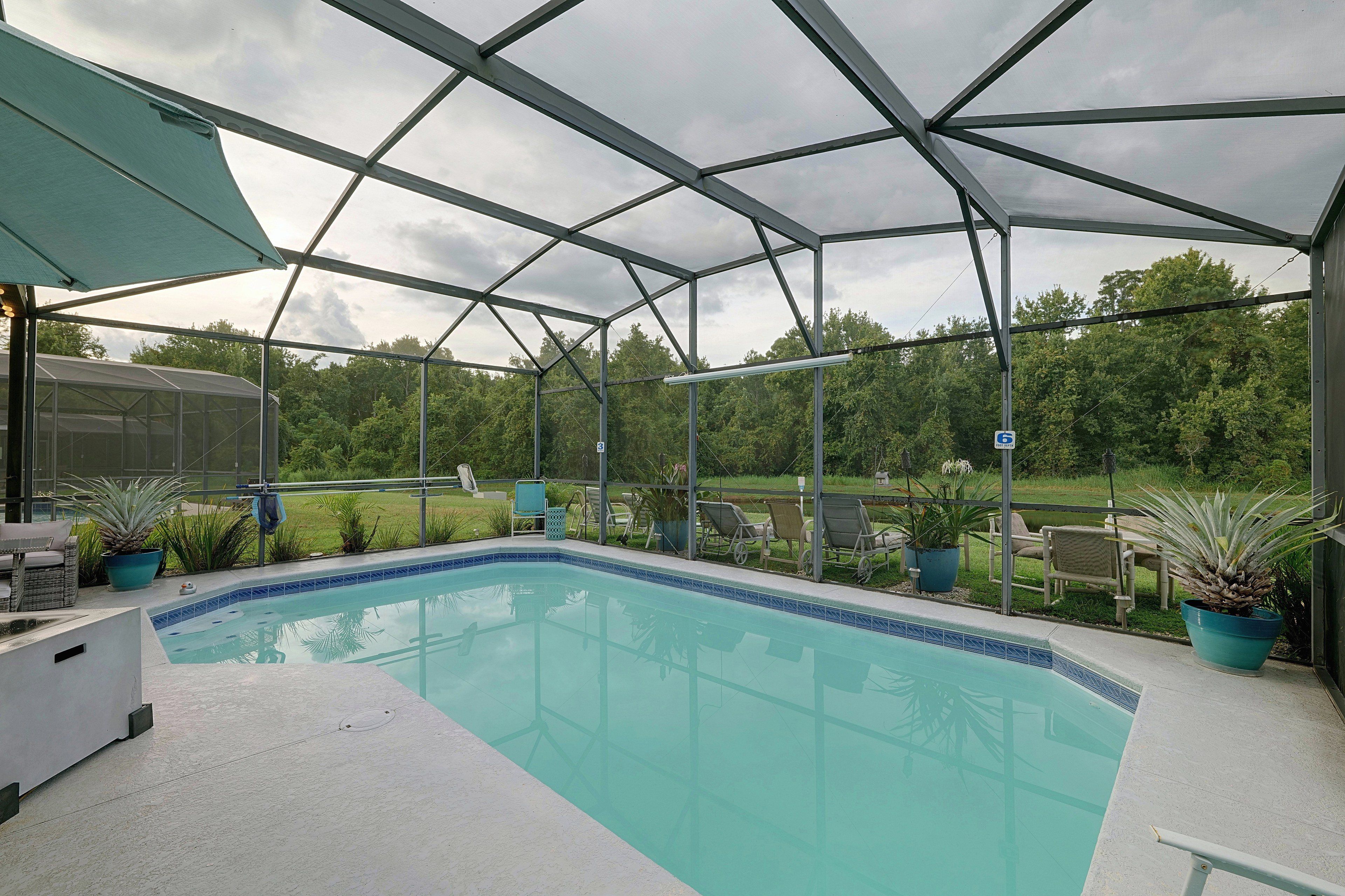 Piscina descoberta coberta, com espreguiçadeiras e plantas em vasos.