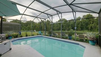 Piscina descoberta coberta, com espreguiçadeiras e plantas em vasos.