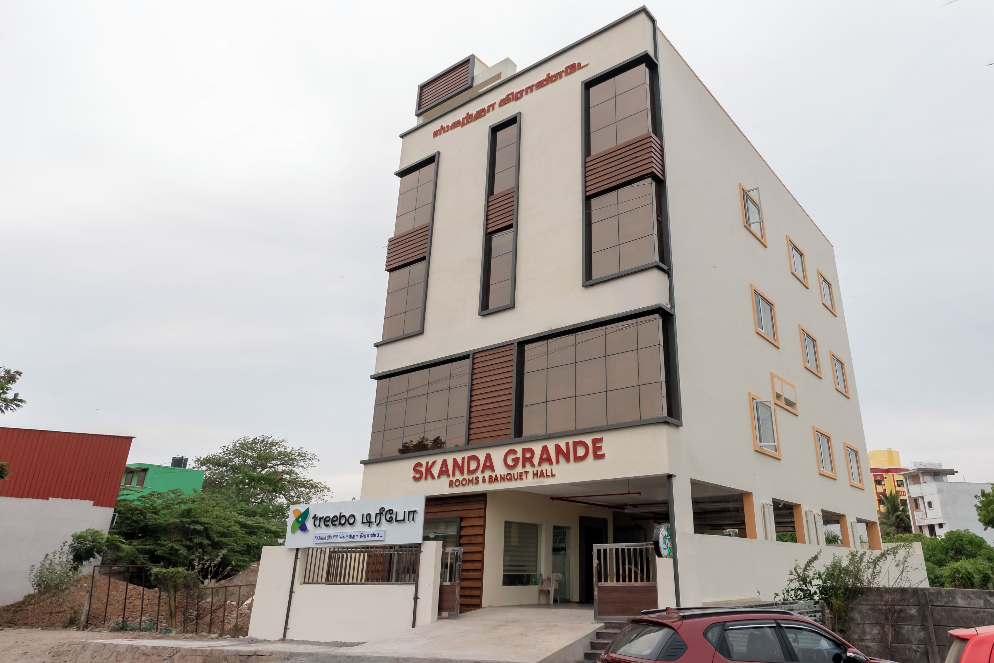 Um edifício de vários andares com uma placa indicando 'Skanda Grande Rooms & Banquet Hall'.