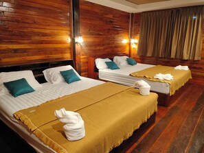 Quarto de hotel com duas camas, paredes de madeira e uma janela com cortinas.