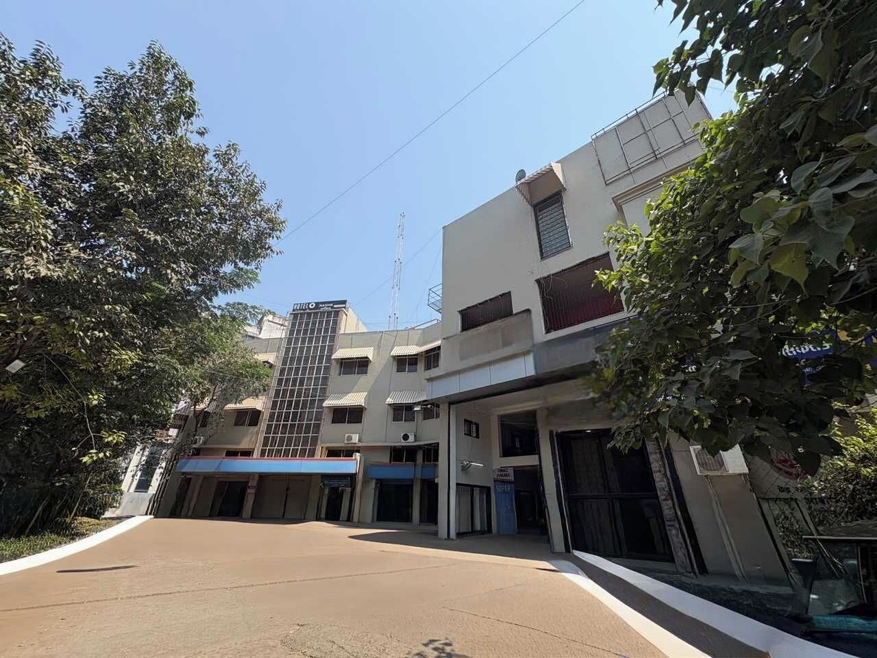 Um edifício de vários andares com fachada plana e múltiplas entradas no nível da rua, sob um céu claro.