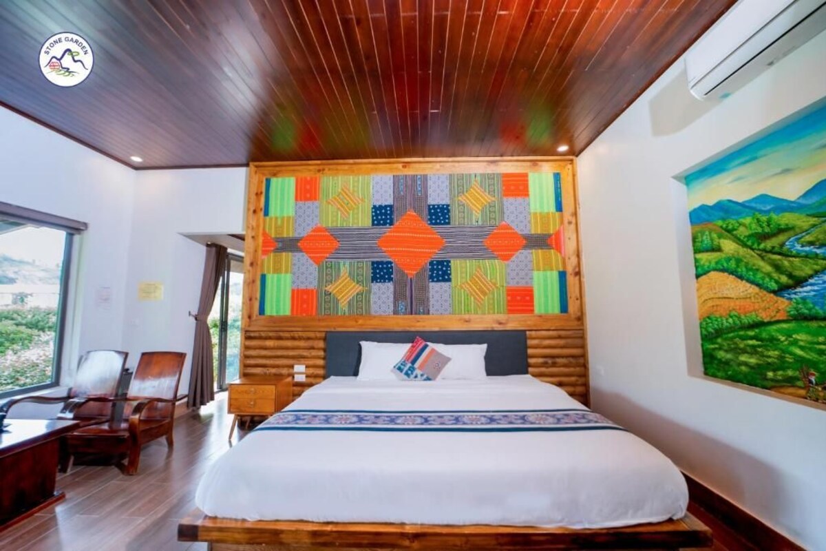 Quarto de hotel com cama, escrivaninha e cadeira.