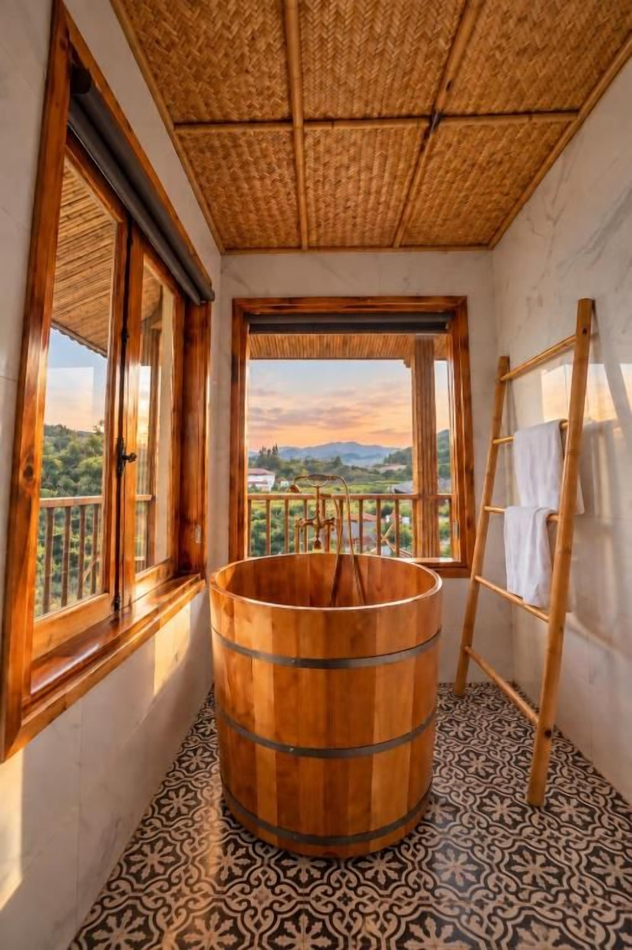 Quarto com um grande barril de madeira, uma escada e janela com vista para o campo.