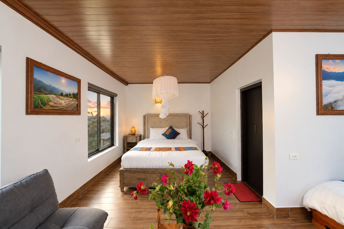 Quarto com cama, mesa de cabeceira, abajur, cadeira, janela e porta.