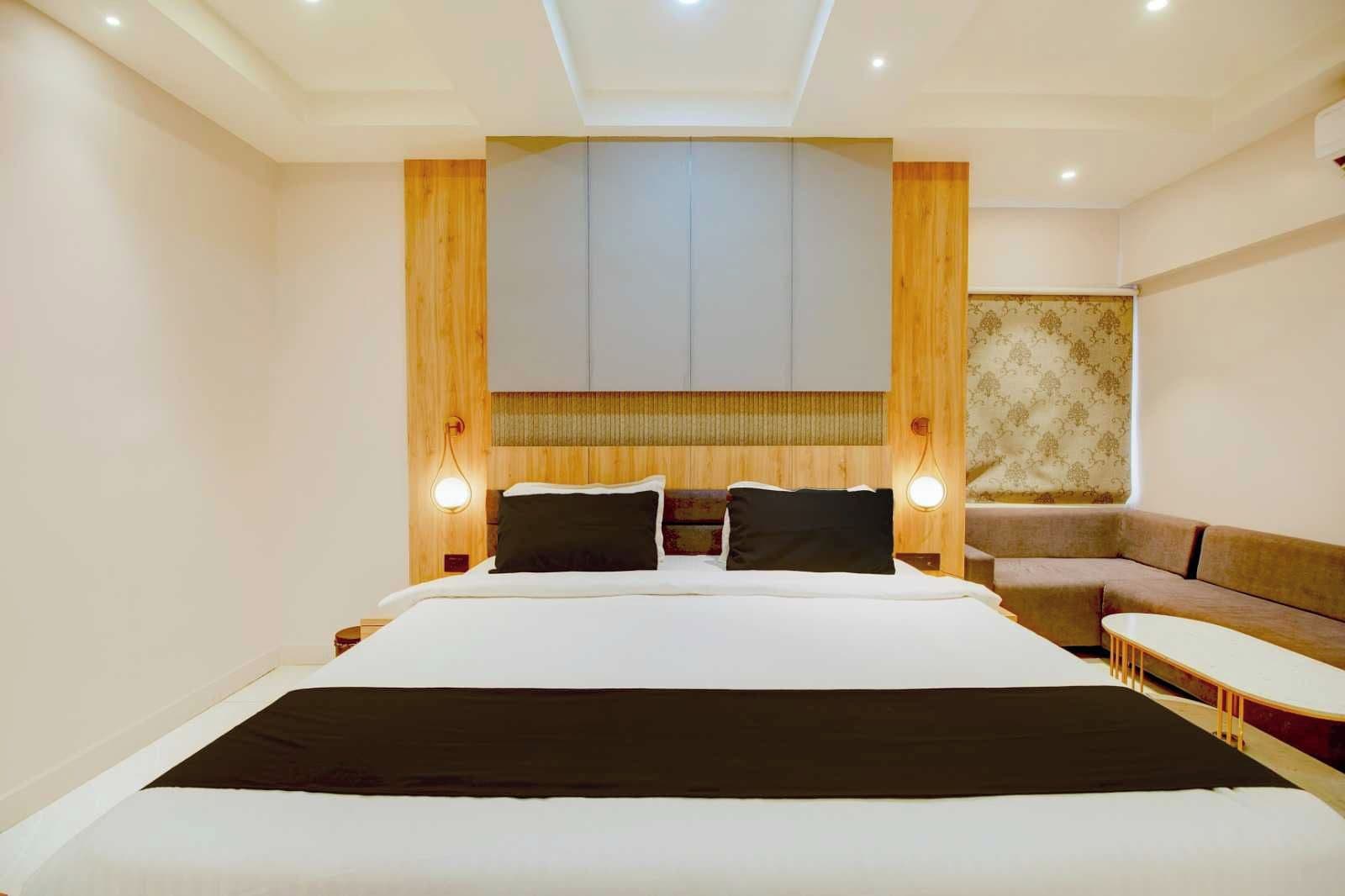 Quarto de hotel com uma cama grande, um sofá e uma mesa pequena.