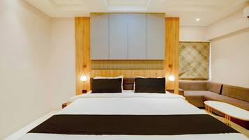Quarto de hotel com uma cama grande, um sofá e uma mesa pequena.
