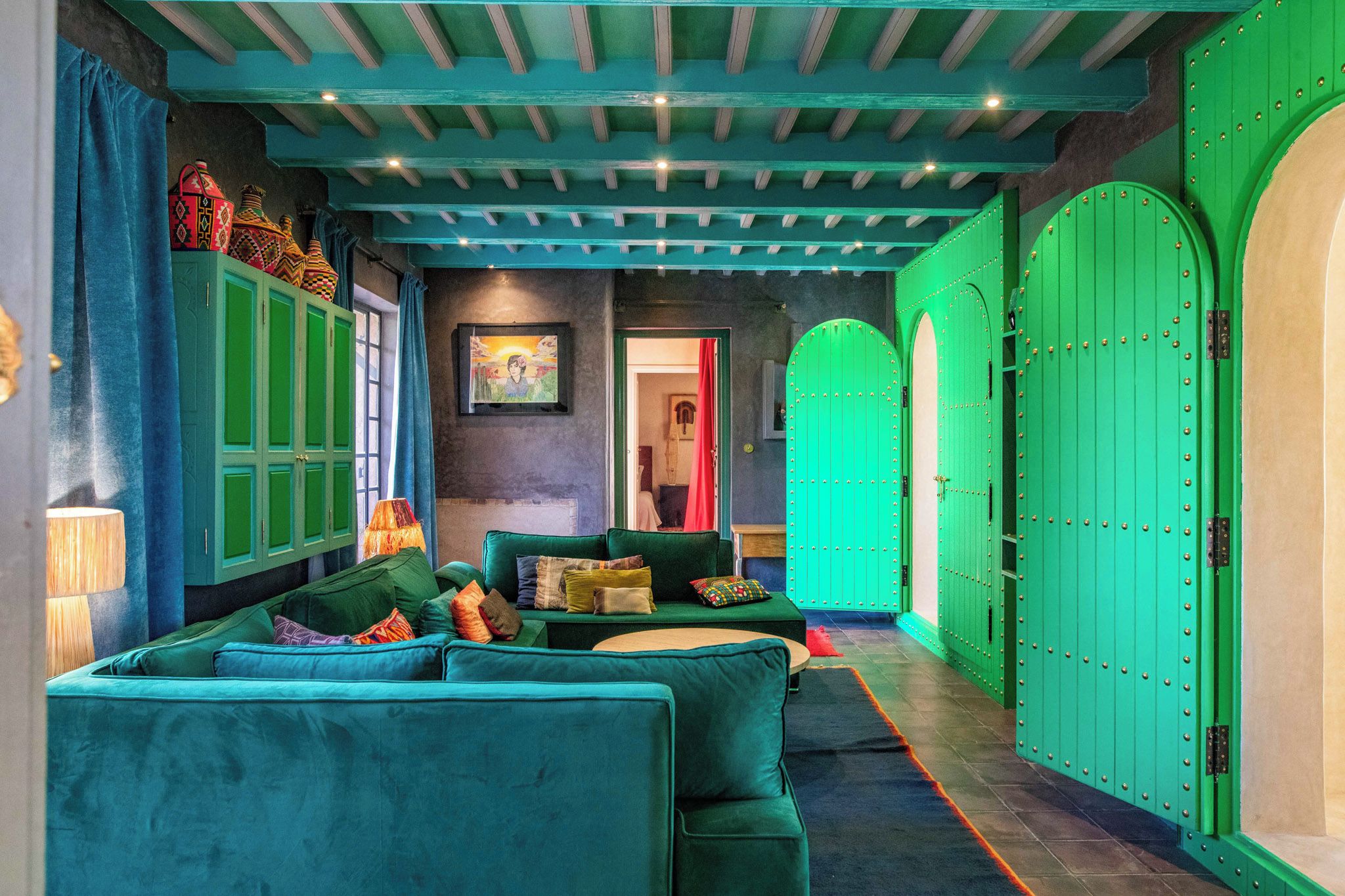 Quarto com sofás verde-água, porta verde e um quadro na parede.
