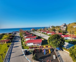 Área residencial costeira com casas, parquinho e vista clara para o mar.