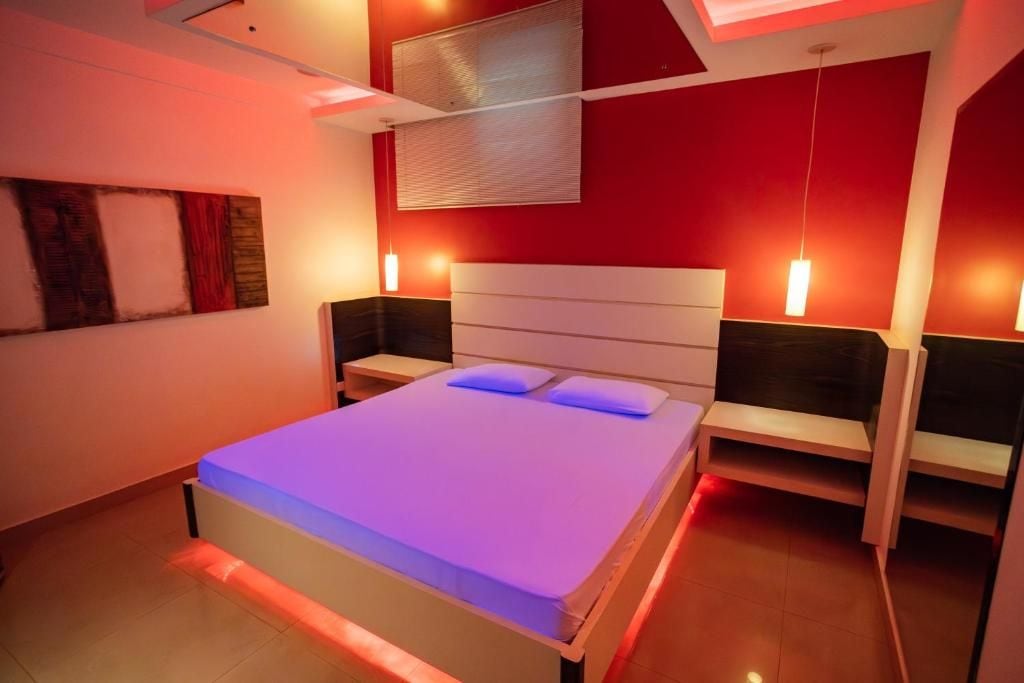 Quarto moderno com cama, mesas de cabeceira e uma obra de arte na parede.