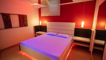 Quarto moderno com cama, mesas de cabeceira e uma obra de arte na parede.