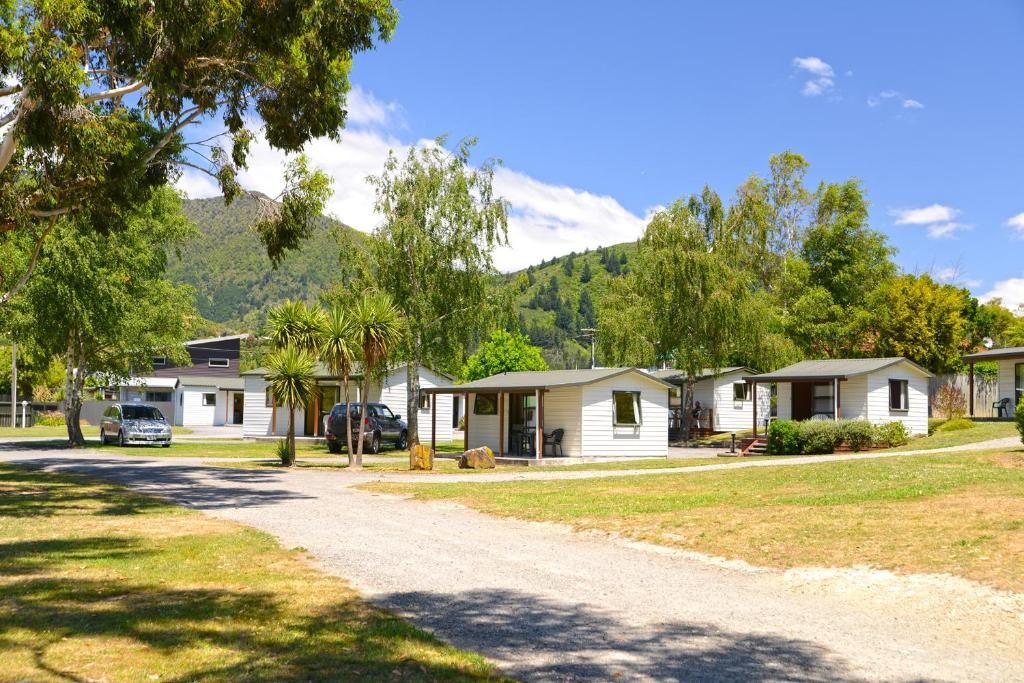 Uma fileira de casas móveis térreas, com um caminho de cascalho, cercada por árvores e uma montanha ao fundo.