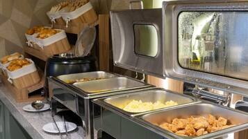 Disposição de buffet com diversos alimentos e utensílios de servir.