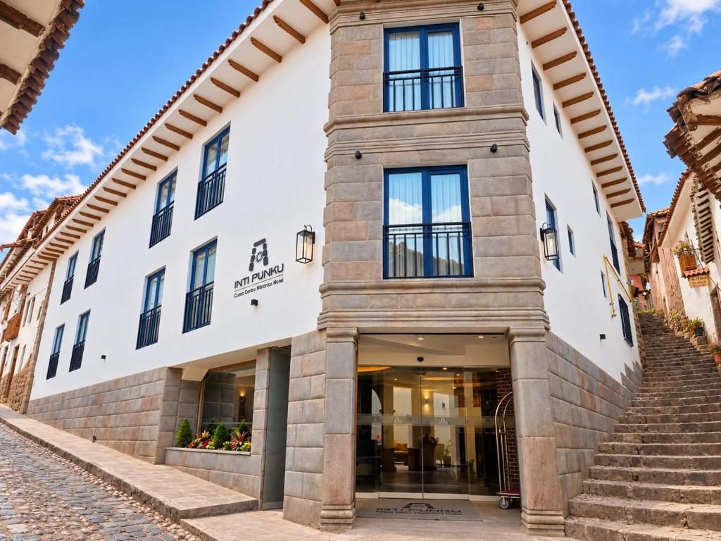 Hotel com fachada branca, várias janelas e escadaria que leva à entrada.