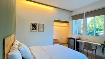 Quarto com cama, escrivaninha, cadeira e janela.