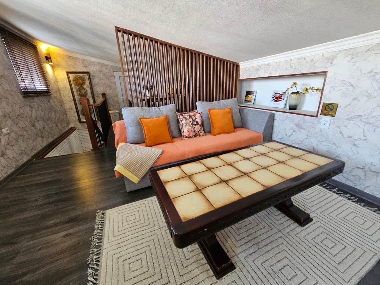 Uma sala de estar moderna com um sofá, uma mesa de centro e um painel decorativo na parede.