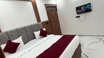 Quarto de hotel com cama, televisão na parede e ventilador de teto.
