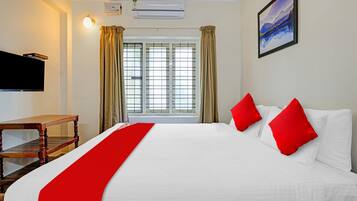 Quarto de hotel com uma cama grande, televisão de tela plana, mesa de cabeceira de madeira e um quadro na parede.