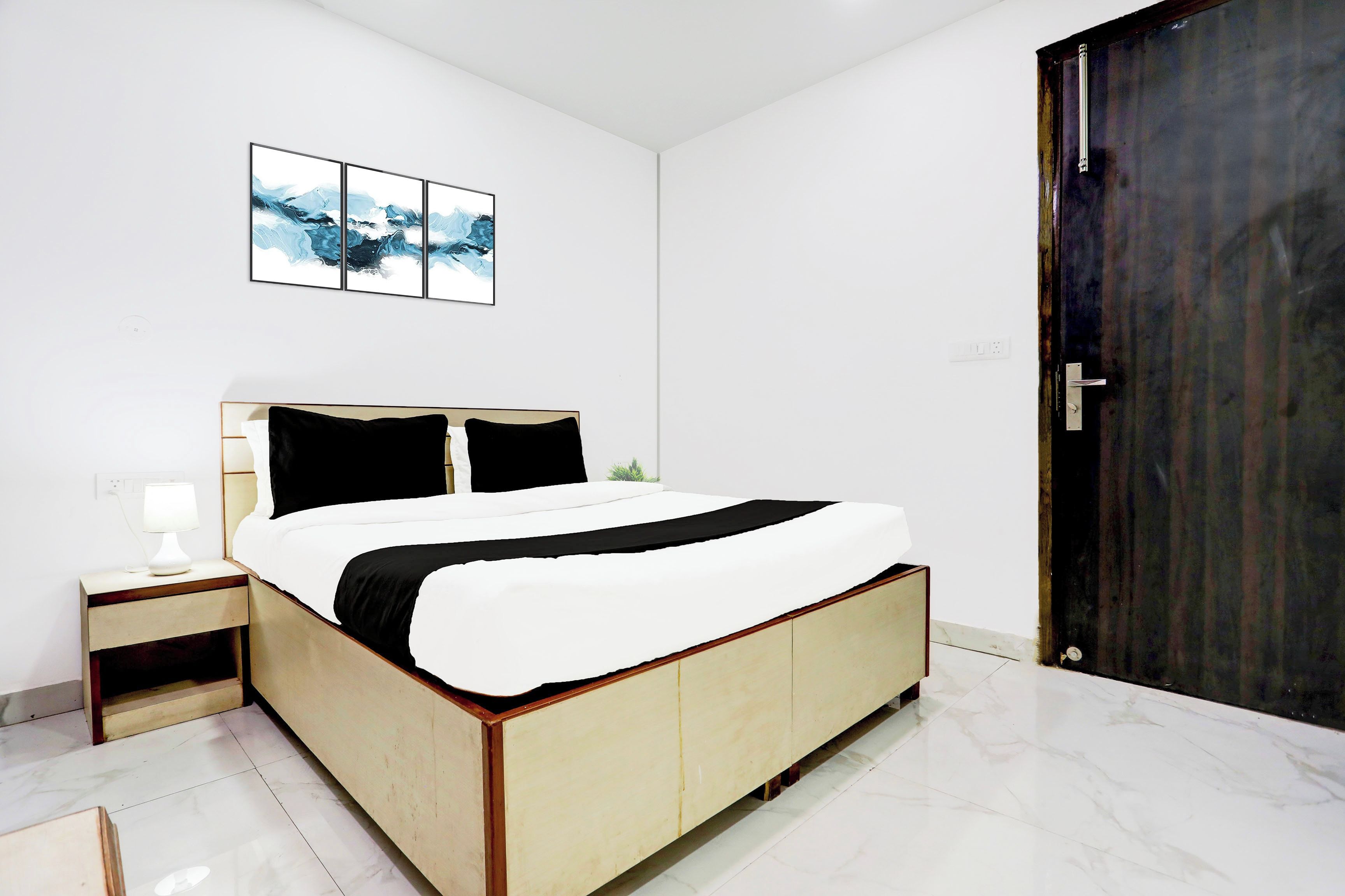 Quarto com cama, mesa de cabeceira, abajur e porta.