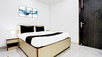 Quarto com cama, mesa de cabeceira, abajur e porta.