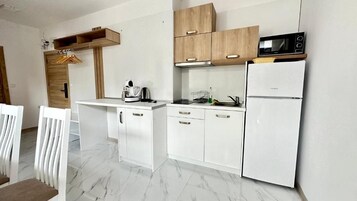 Cozinha moderna com armários brancos, micro-ondas e geladeira.