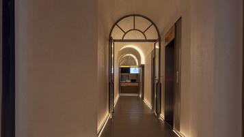 Corredor de hotel com design moderno, apresentando um longo hall com tetos arqueados e um caminho central.