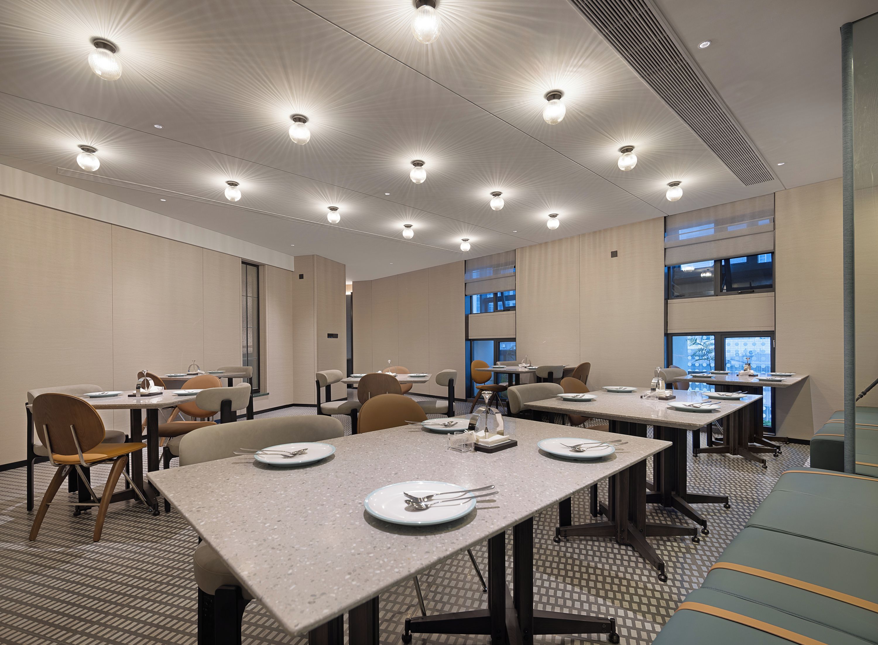 Uma sala de conferências de hotel com várias mesas e cadeiras, equipada com pratos e talheres.