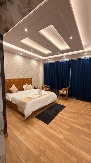 Quarto moderno com uma cama grande, piso de madeira e teto com iluminação embutida.
