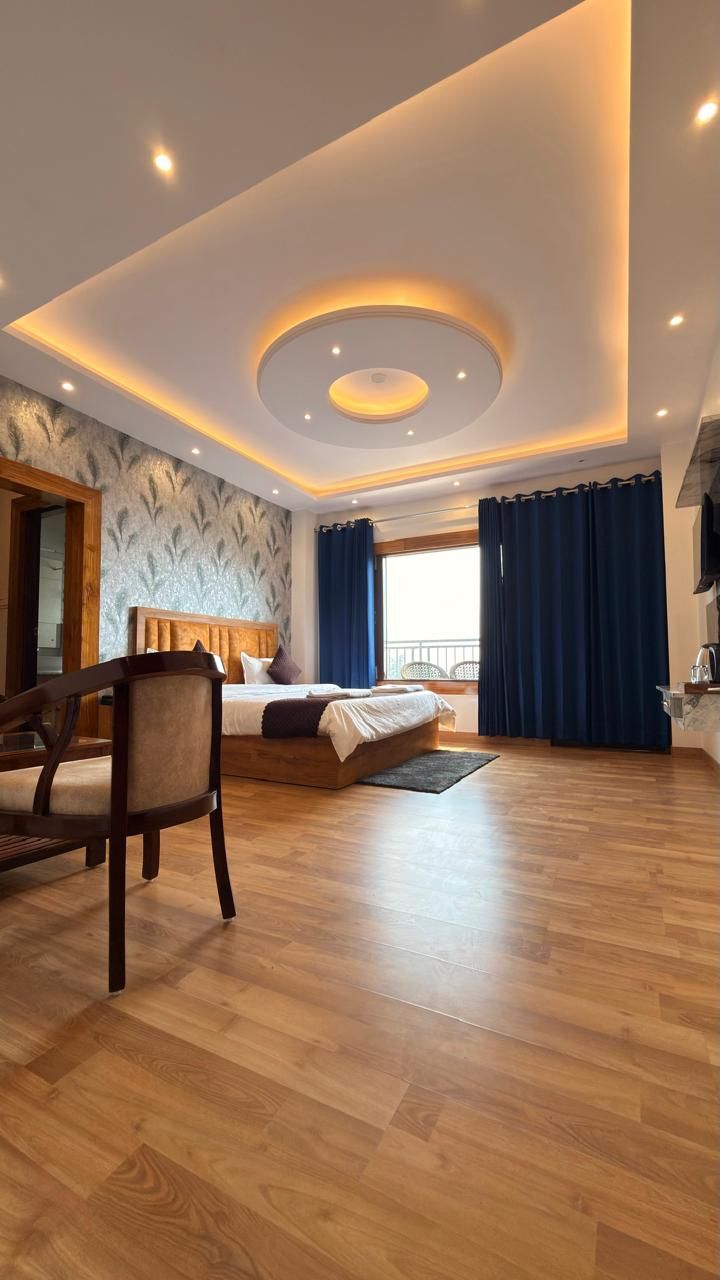 Quarto de hotel moderno com piso de madeira, uma cama grande, escrivaninha e vista para o exterior.