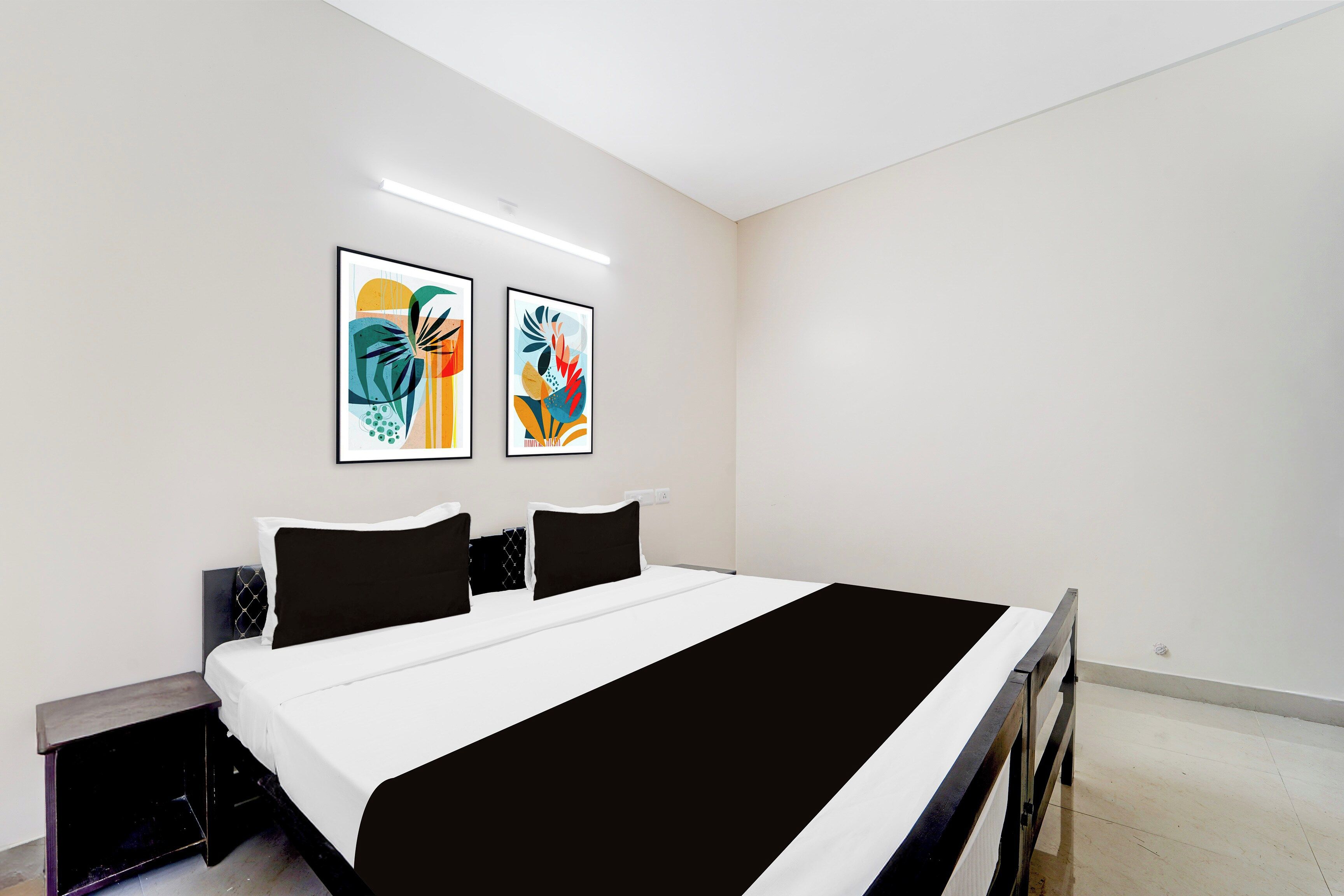Quarto moderno com uma cama grande, duas obras de arte penduradas na parede e uma mesa de cabeceira.