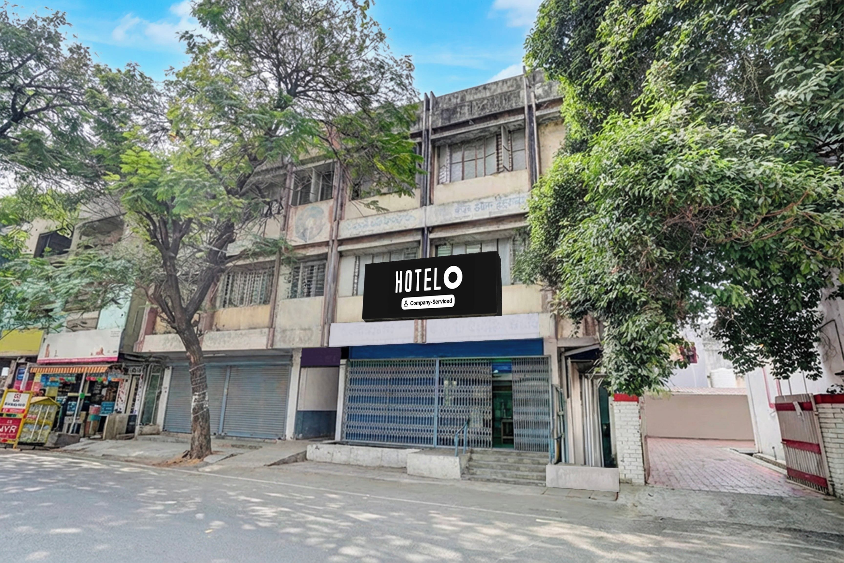 Hotel com placa, entrada gradeada e vista da rua.
