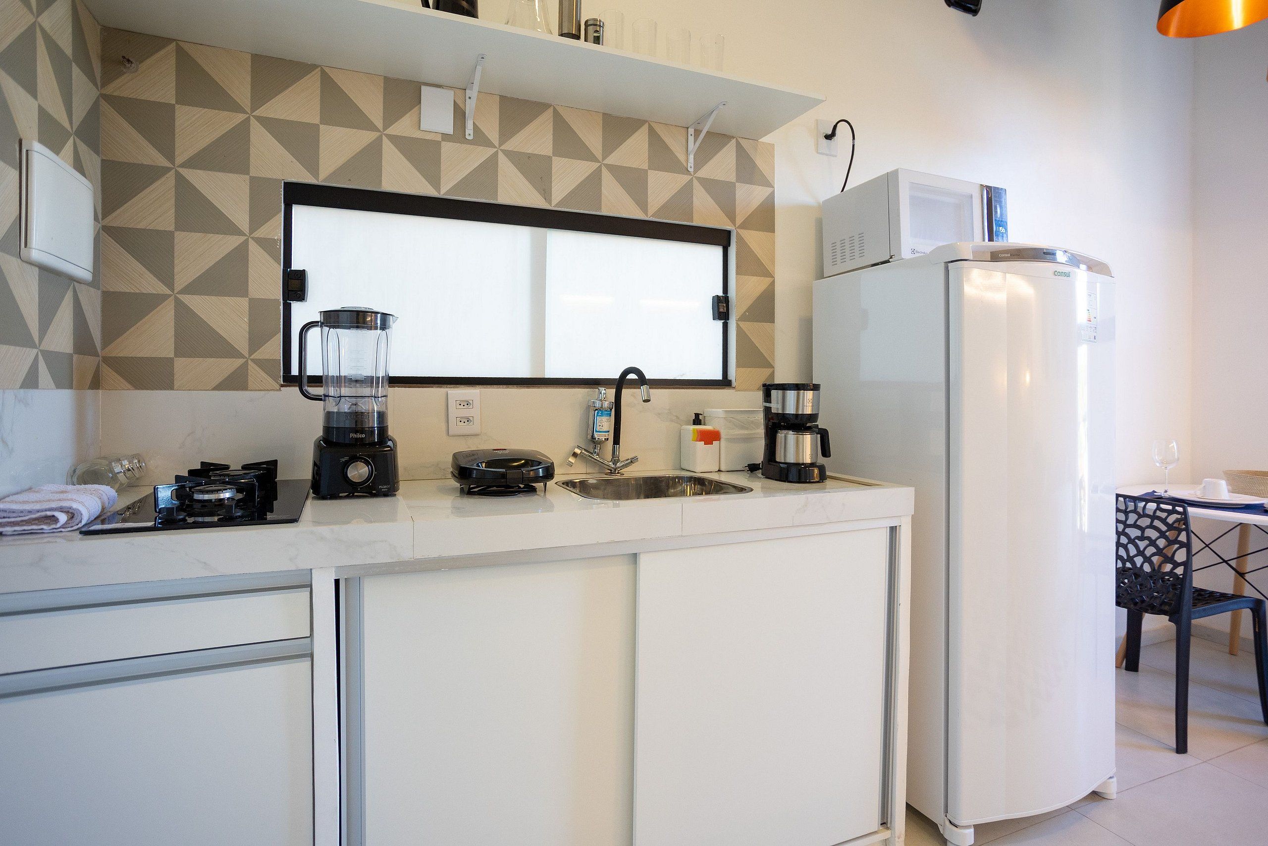 Cozinha moderna com máquina de lavar louça embutida, cafeteira e liquidificador na bancada.