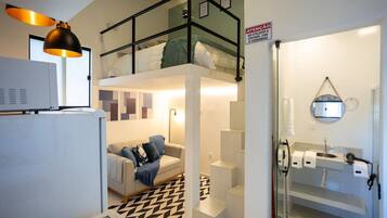 Apartamento compacto e moderno, com quarto no mezanino, cozinha americana e banheiro.
