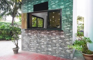 Edifício com fachada de pedra e janela com vista para vegetação.