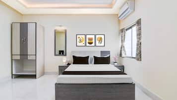 Quarto moderno com uma cama grande, guarda-roupa, mesa de cabeceira, espelho e quadros nas paredes.