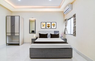 Quarto moderno com uma cama grande, guarda-roupa, mesa de cabeceira, espelho e quadros nas paredes.