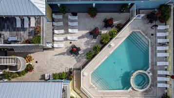 Vista aérea de uma área de piscina no terraço, com cadeiras de sol, piscina e escada que leva a um deck superior.