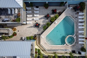 Vista aérea de uma área de piscina no terraço, com cadeiras de sol, piscina e escada que leva a um deck superior.