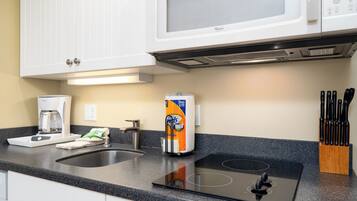 Cozinha equipada com micro-ondas, cafeteira, pia e fogão por indução.