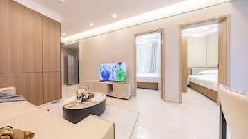 Quarto de hotel moderno com televisão de tela plana, sofá, cama e banheiro com cortina de chuveiro.