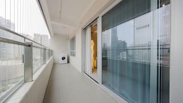 Corredor com máquina de lavar, porta de vidro deslizante e vista para a paisagem urbana.