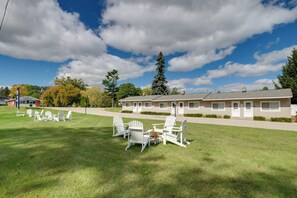 Um motel com gramado e cadeiras brancas.