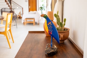 Uma mesa de madeira com uma escultura de pássaro colorido e um cacto em vaso.