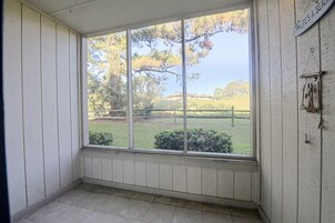 Quarto com uma janela grande, paredes brancas e piso de azulejos.