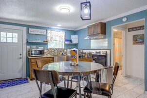 Cozinha com mesa de jantar, cadeiras, micro-ondas, fogão e luminária pendente.