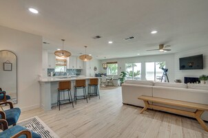 Cozinha moderna com ilha central, banquetas de bar e área de refeições com vista.