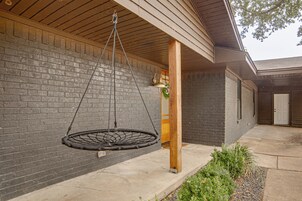 Um balanço pendurado em um teto de madeira, uma parede de tijolos e uma porta com janela.