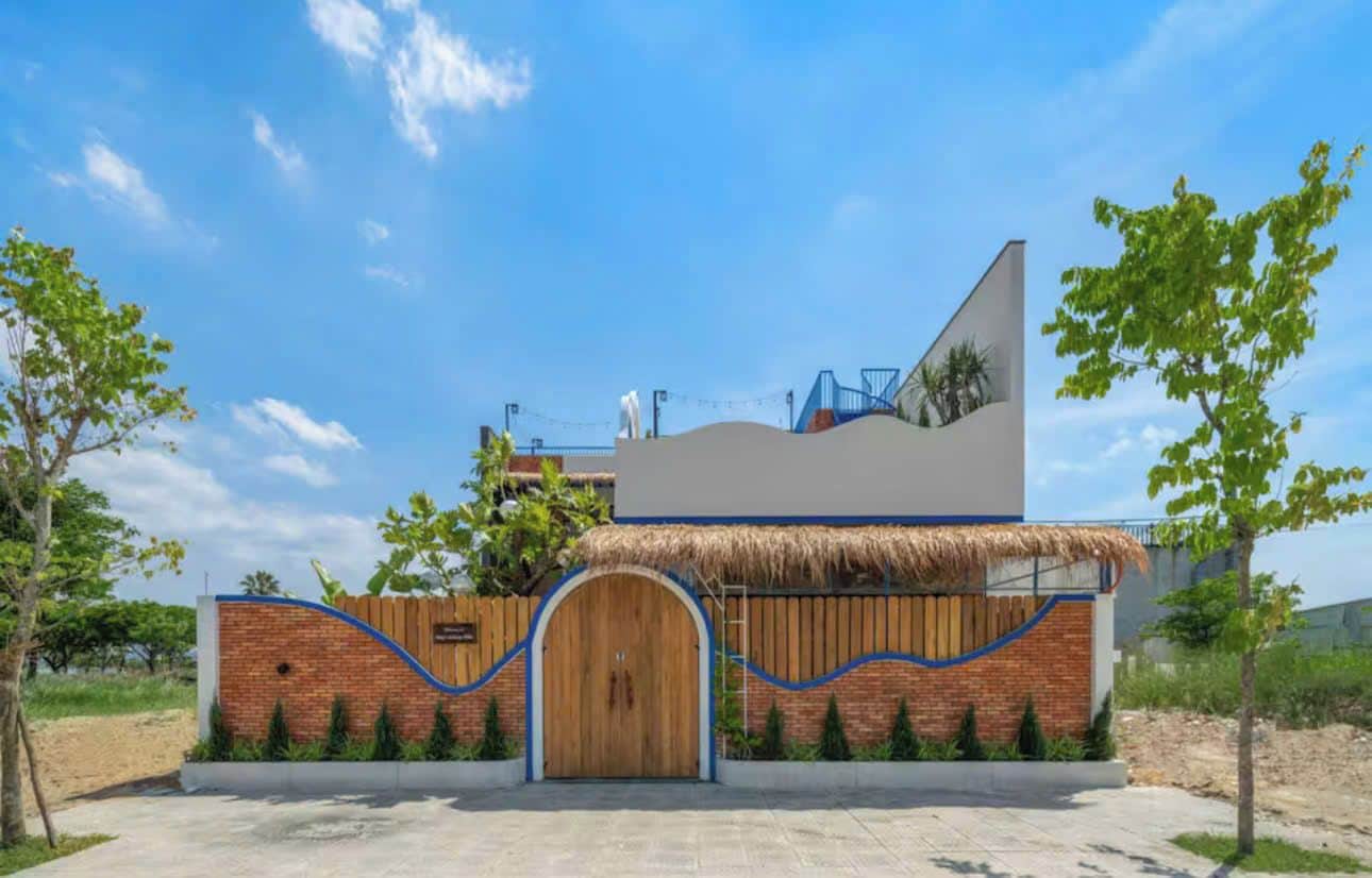 Um edifício moderno com entrada de telhado de palha, paredes de tijolo e design curvo.
