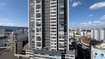 Um edifício alto com várias varandas, cercado por outros edifícios e um céu claro.